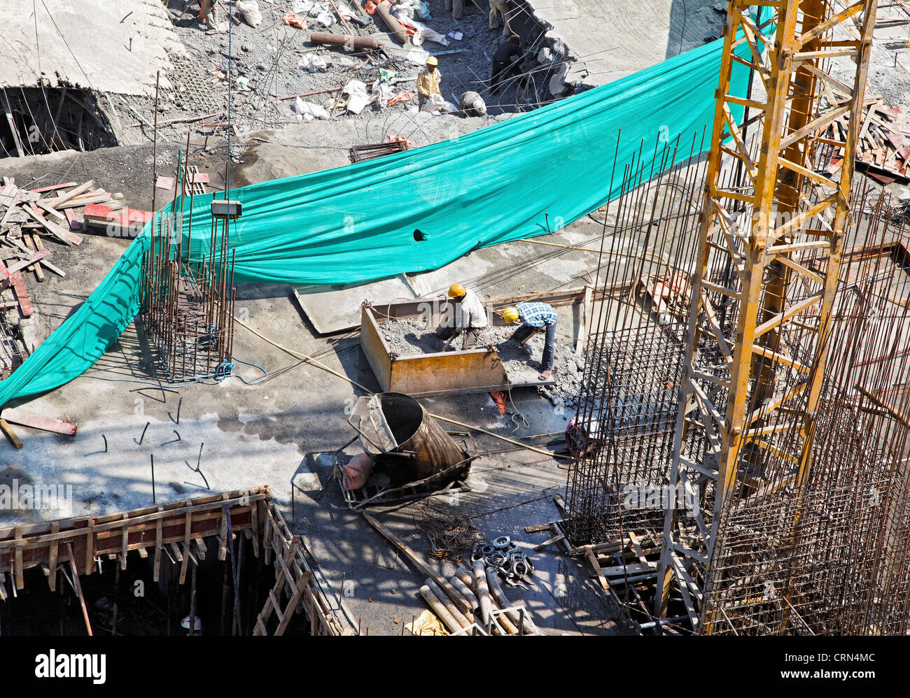 Overhead of building workers clearing builders rubble into a skip of a ...