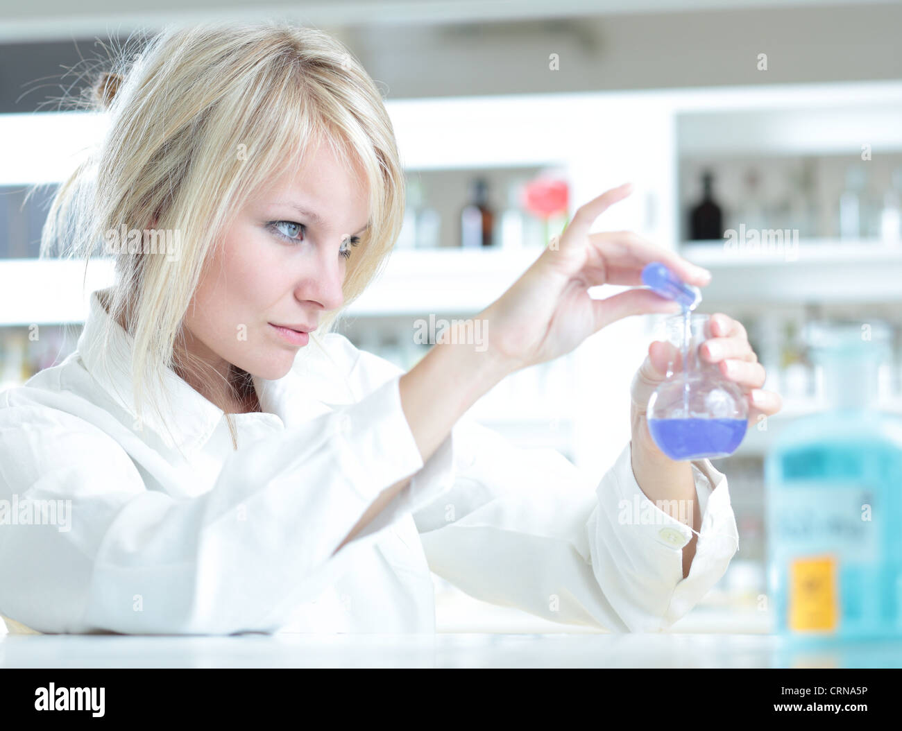 Closeup of a female researcher holding up a test tube and a retort and ...