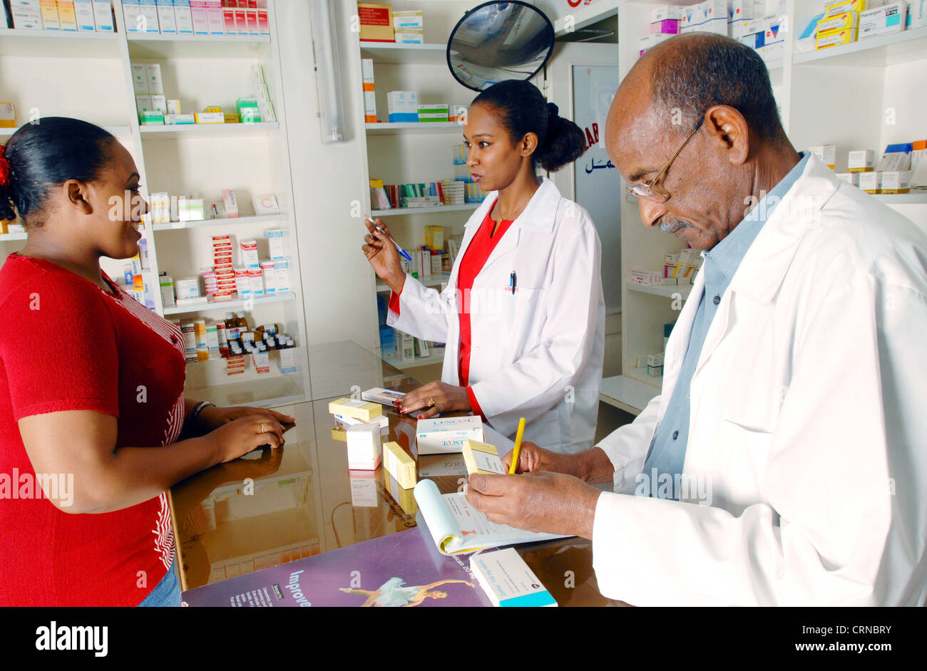 Male pharmacist prepares a patients prescription. Female assistant ...