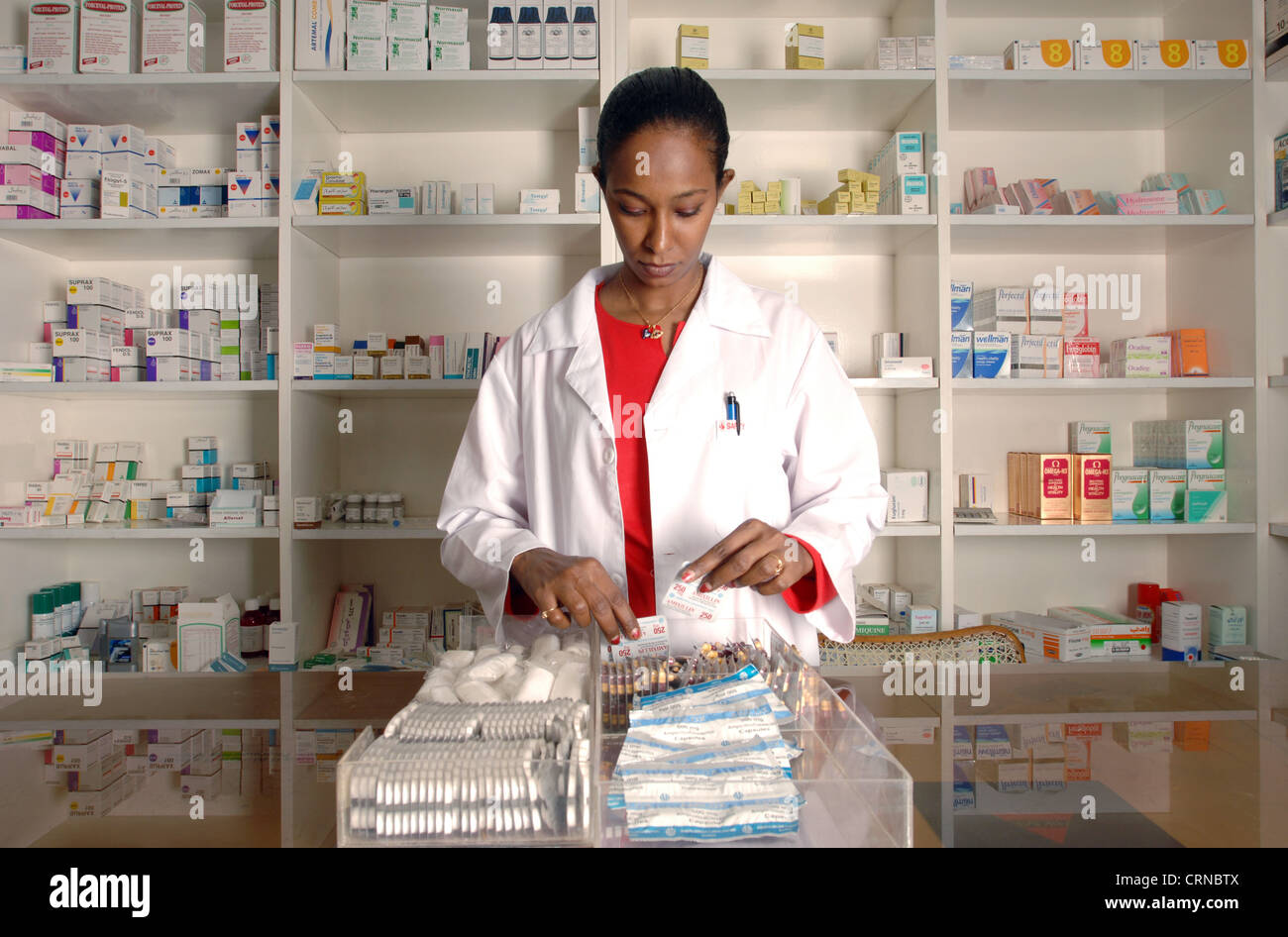 A female pharmacist assistant sorts prescription drugs into categories ...