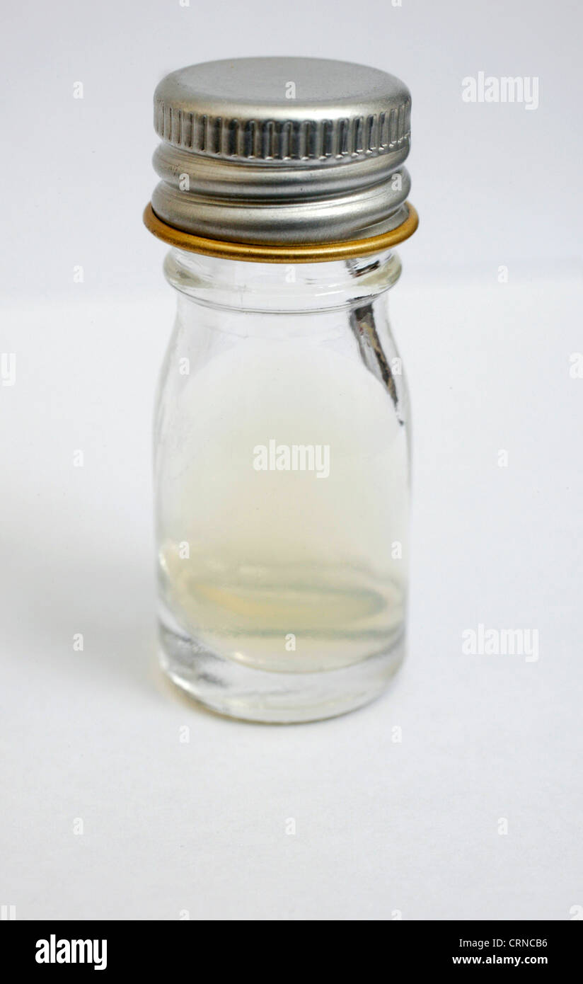 Small clear glass bottle containg a clear liquid Stock Photo - Alamy