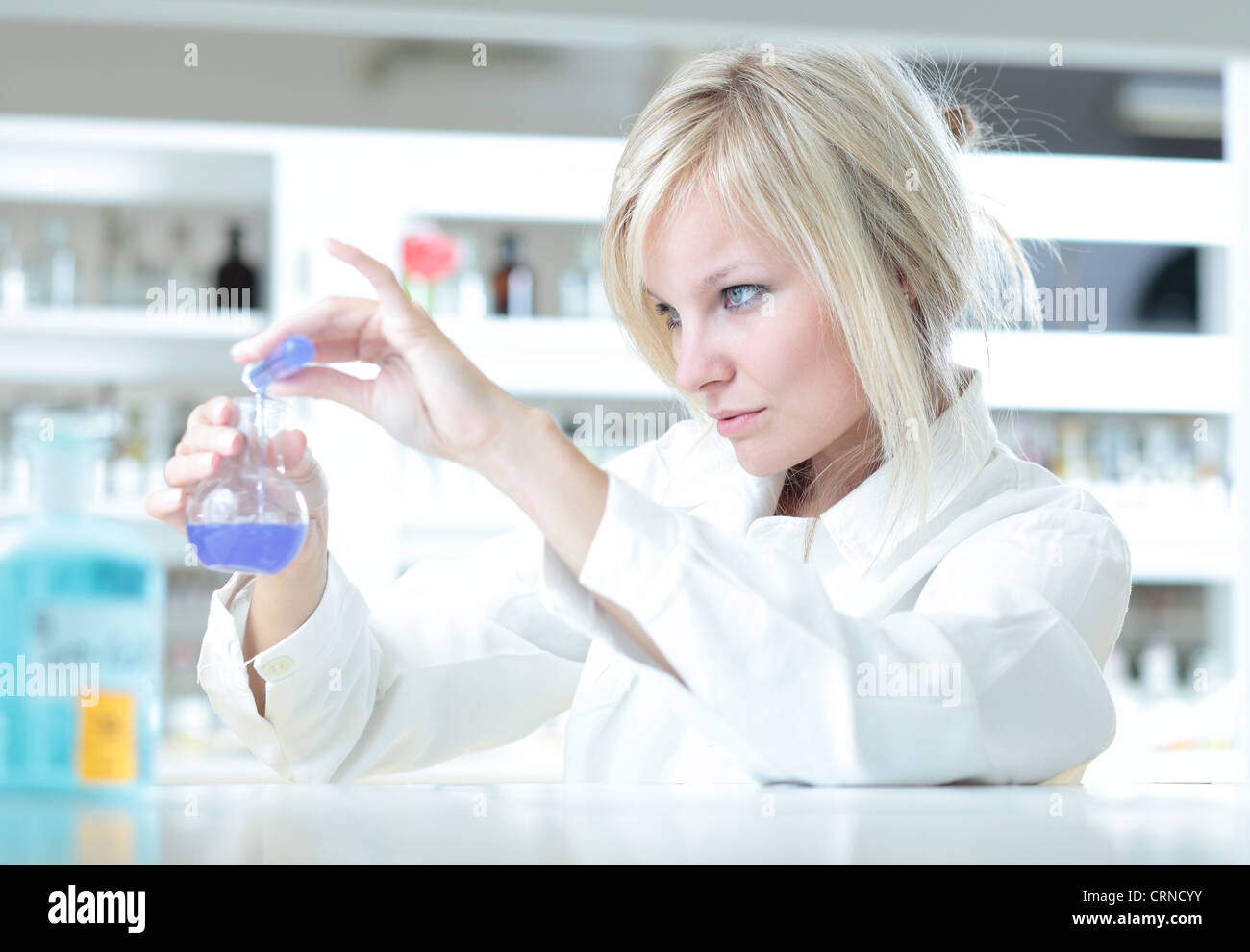 Closeup of a female researcher holding up a test tube and a retort and ...