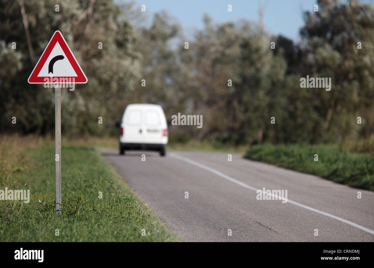 White pick-up going on a contryside road with a sharp corner sign on a ...