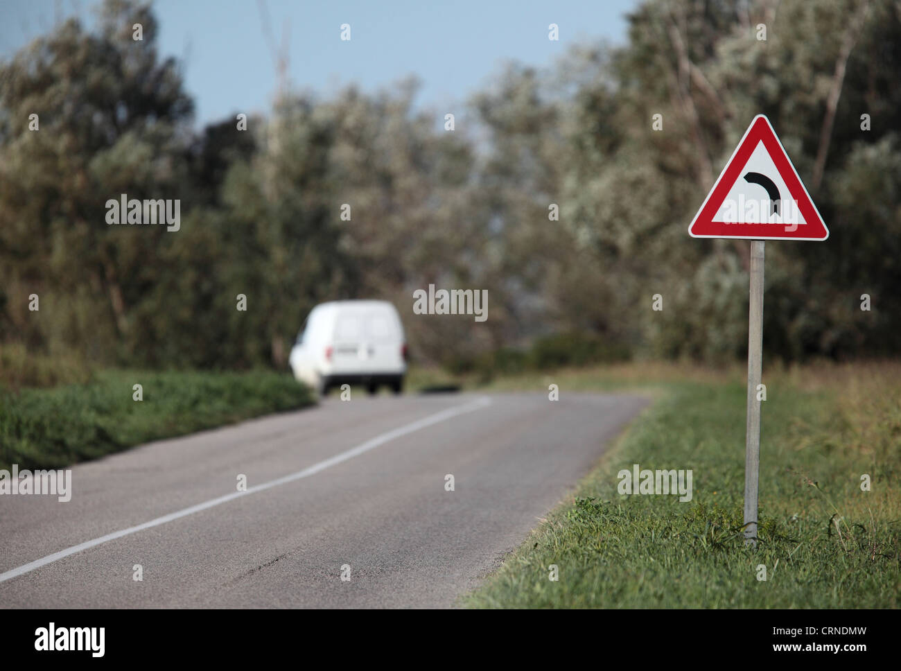White pick-up going on a contryside road with a sharp corner sign on a ...