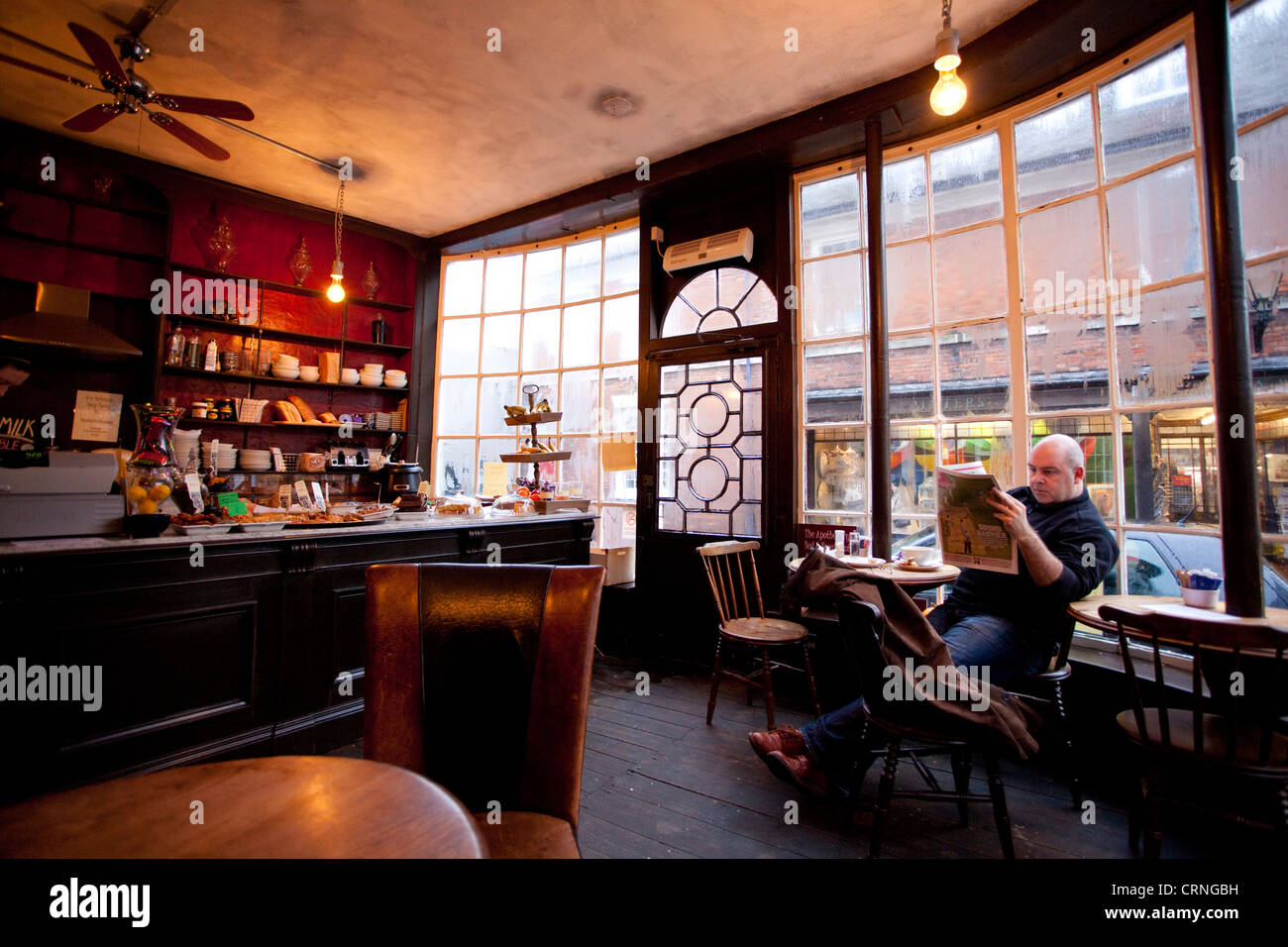 A man relaxing reading a newspaper in the Apothecary cafe in Rye Stock ...