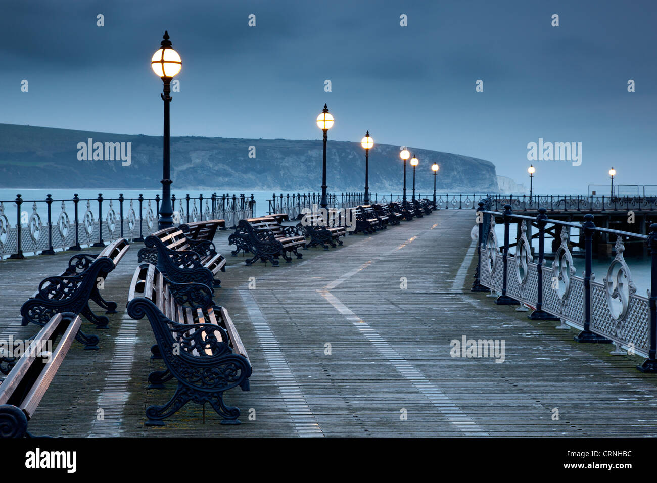 Benches under lamps along Swanage pier at twilight Stock Photo - Alamy