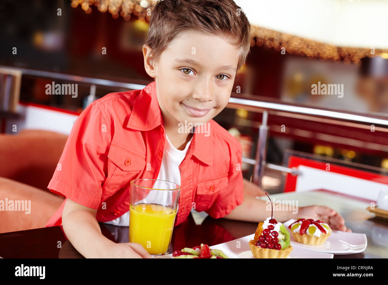 Portrait of a cute boy with three portions of dessert at the cafe Stock ...