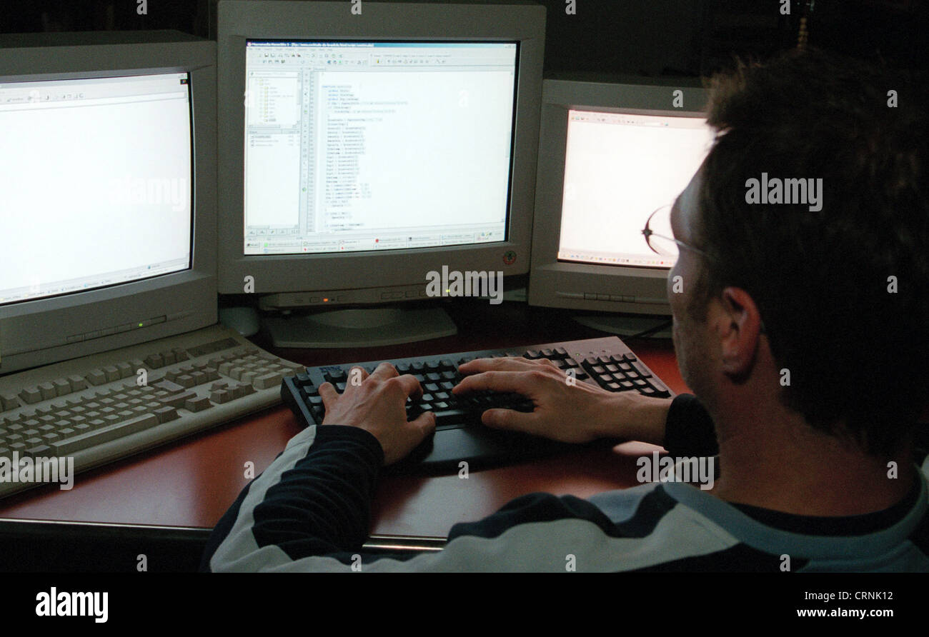 A young man sitting in front of computer monitors Stock Photo - Alamy