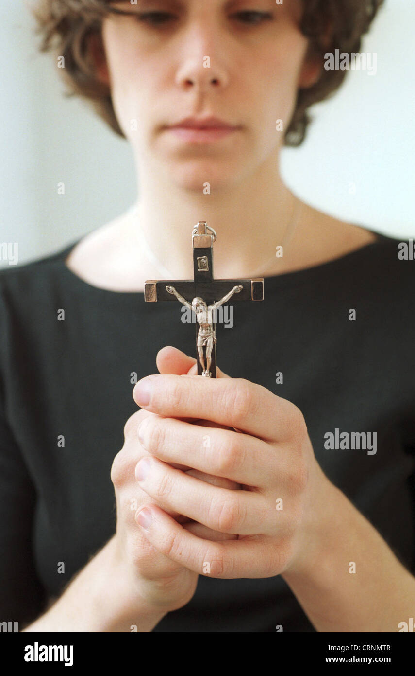 A young woman praying with a crucifix Stock Photo - Alamy