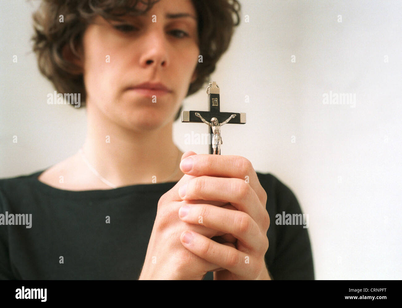 A young woman praying with a crucifix Stock Photo - Alamy