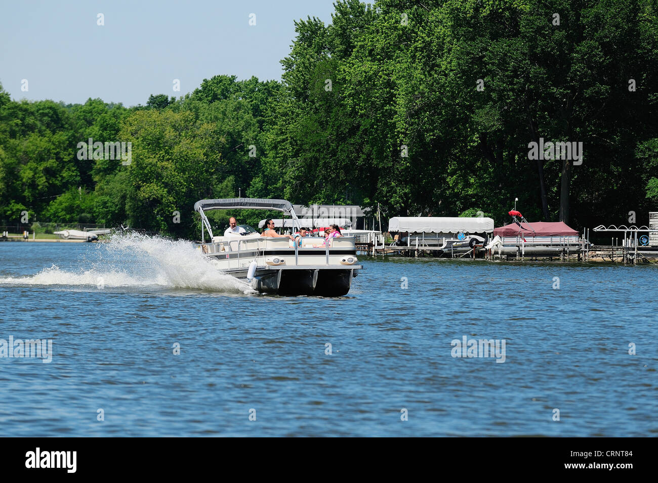 Pontoon boat cruising along shoreline Stock Photo - Alamy