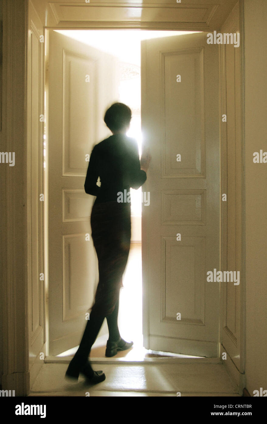 Woman opens door to a brightly lit room Stock Photo - Alamy
