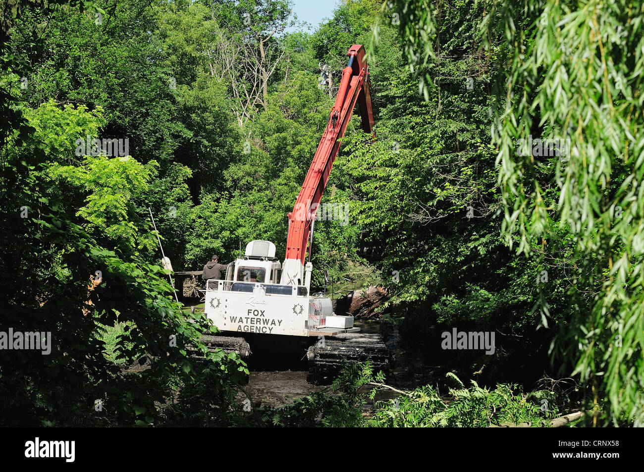 Crane clearing channel debris from an overgrown canal off the Fox River ...