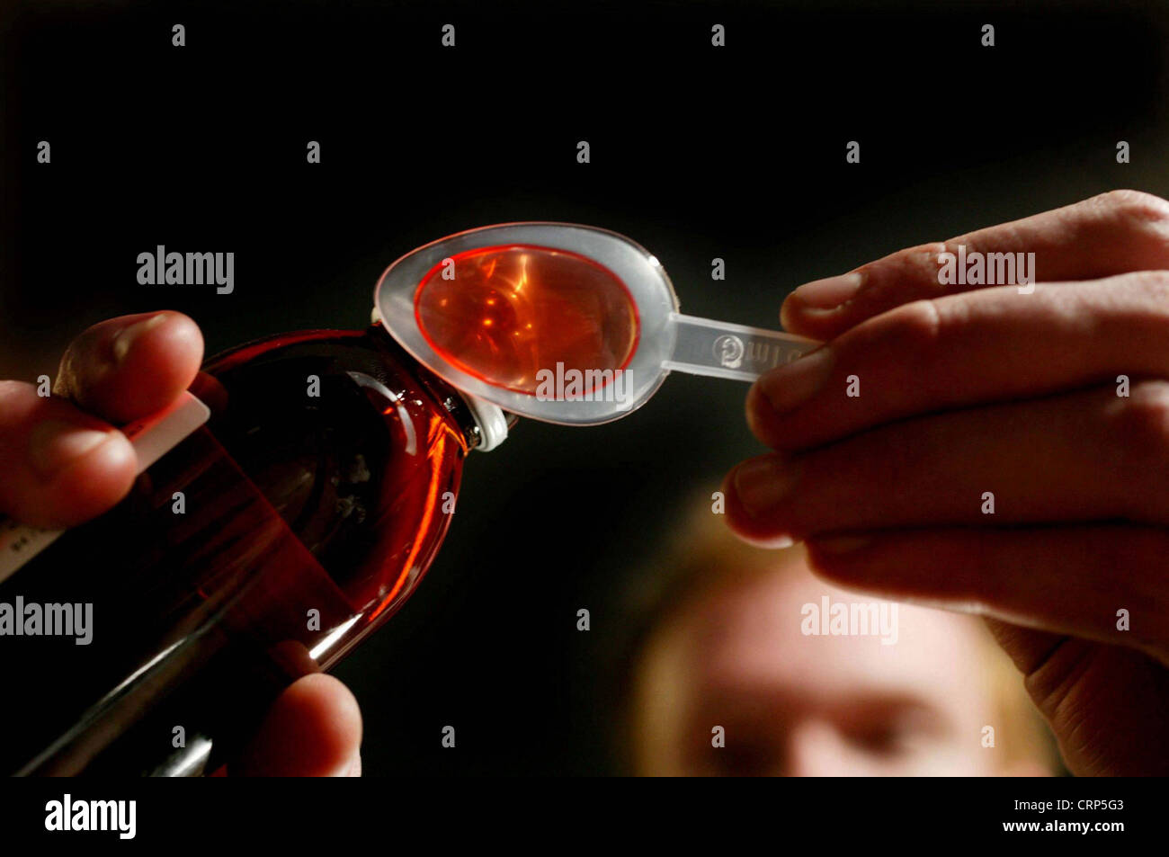 Pouring a liquid medicine from a bottle into a 5 millilitre spoon that ...