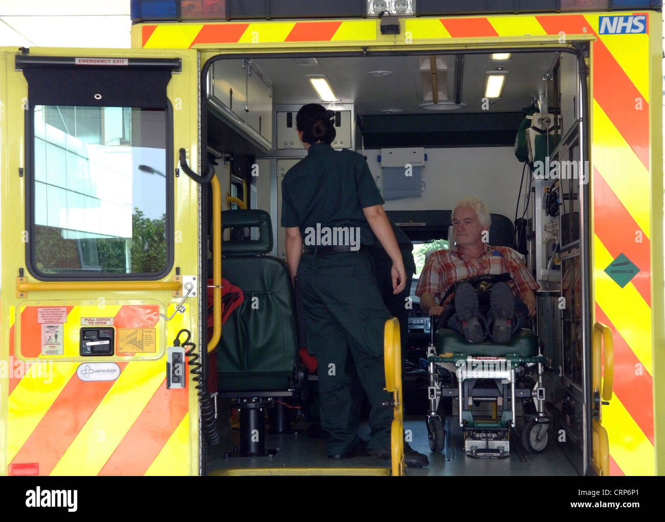 A male patient on trolley in the back of an NHS London ambulance with a ...