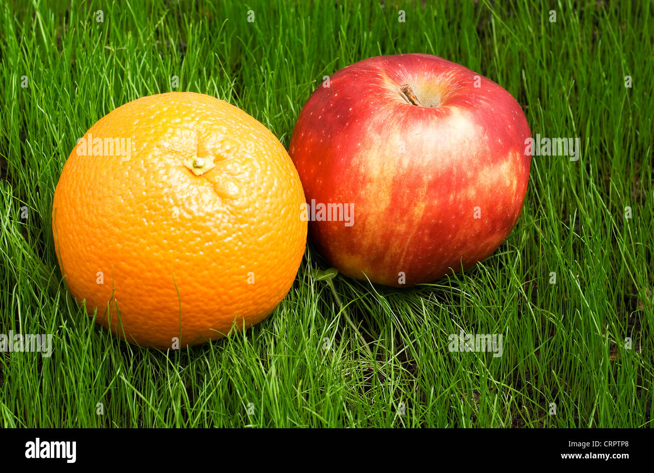 orange and red apple on green grass Stock Photo - Alamy