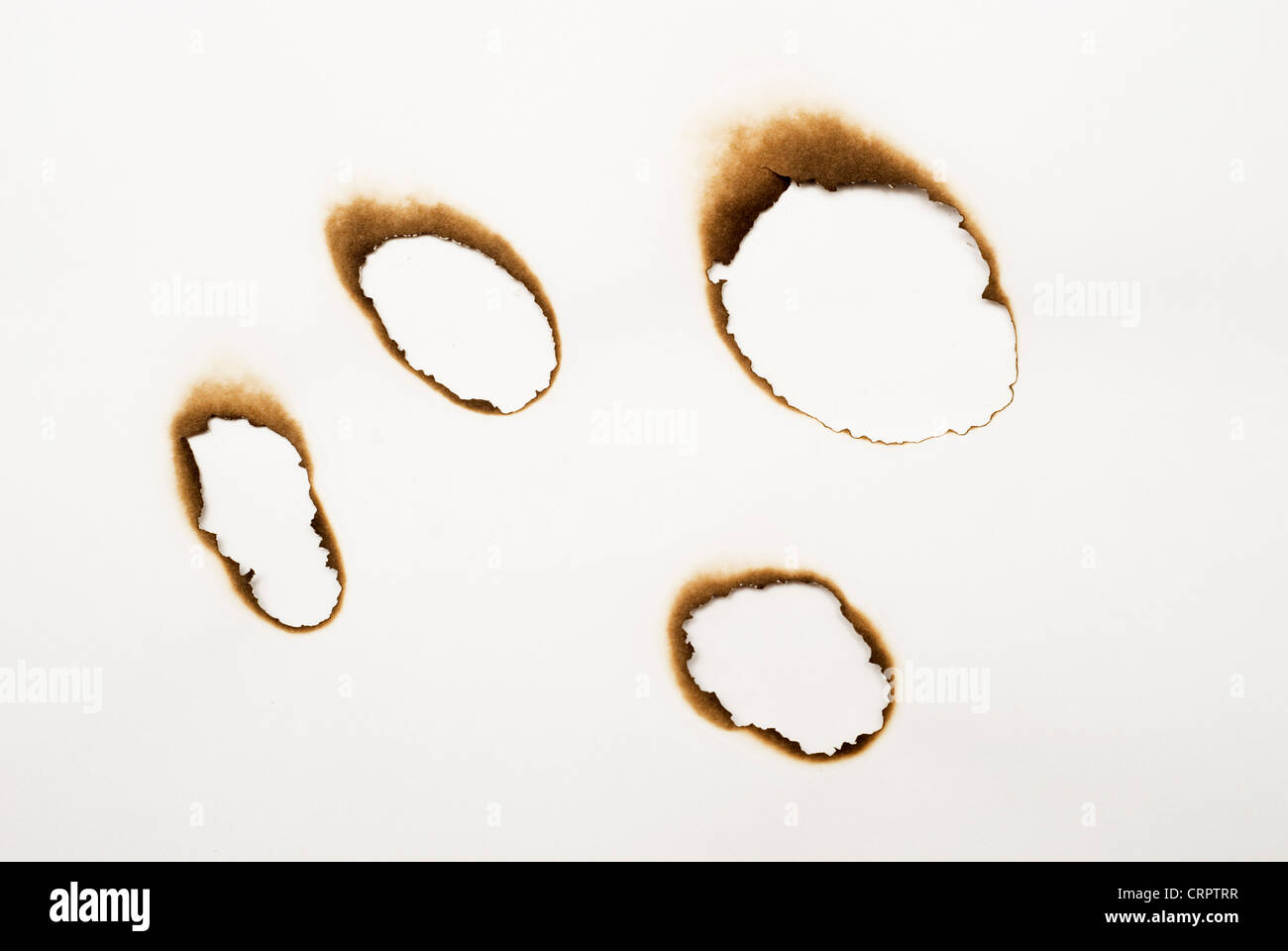 four burned holes in a paper Stock Photo - Alamy