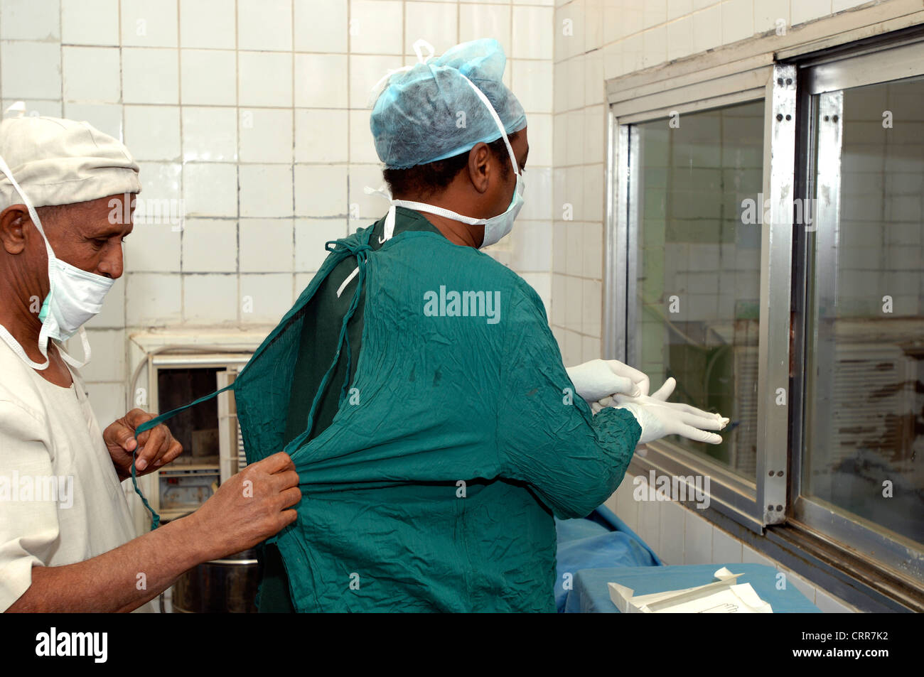 A surgeon's assistant helps to tie up the surgeons scrubs prior to ...