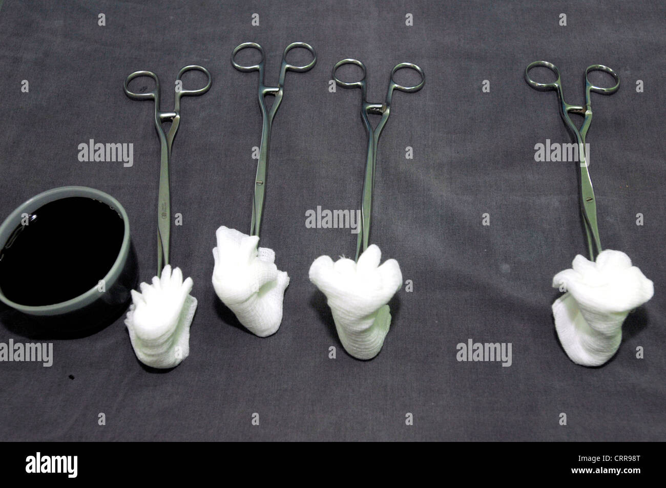 Iodine solution in bowl with sterile swabs on holders to sterilize area ...