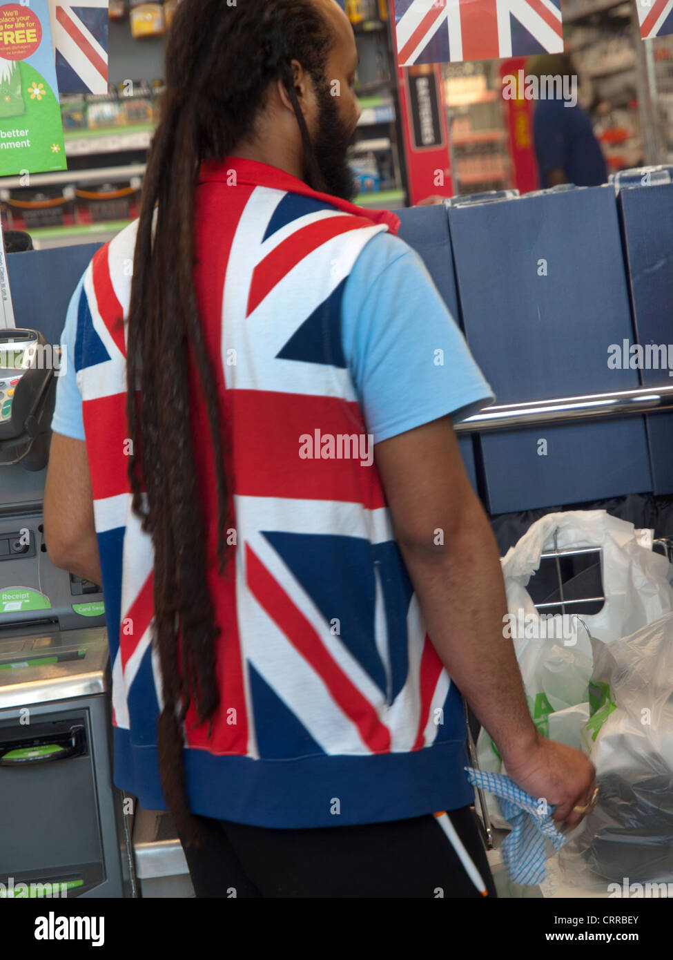 In a supermarket a check-out worker wears a Union Jack jacket Stock ...