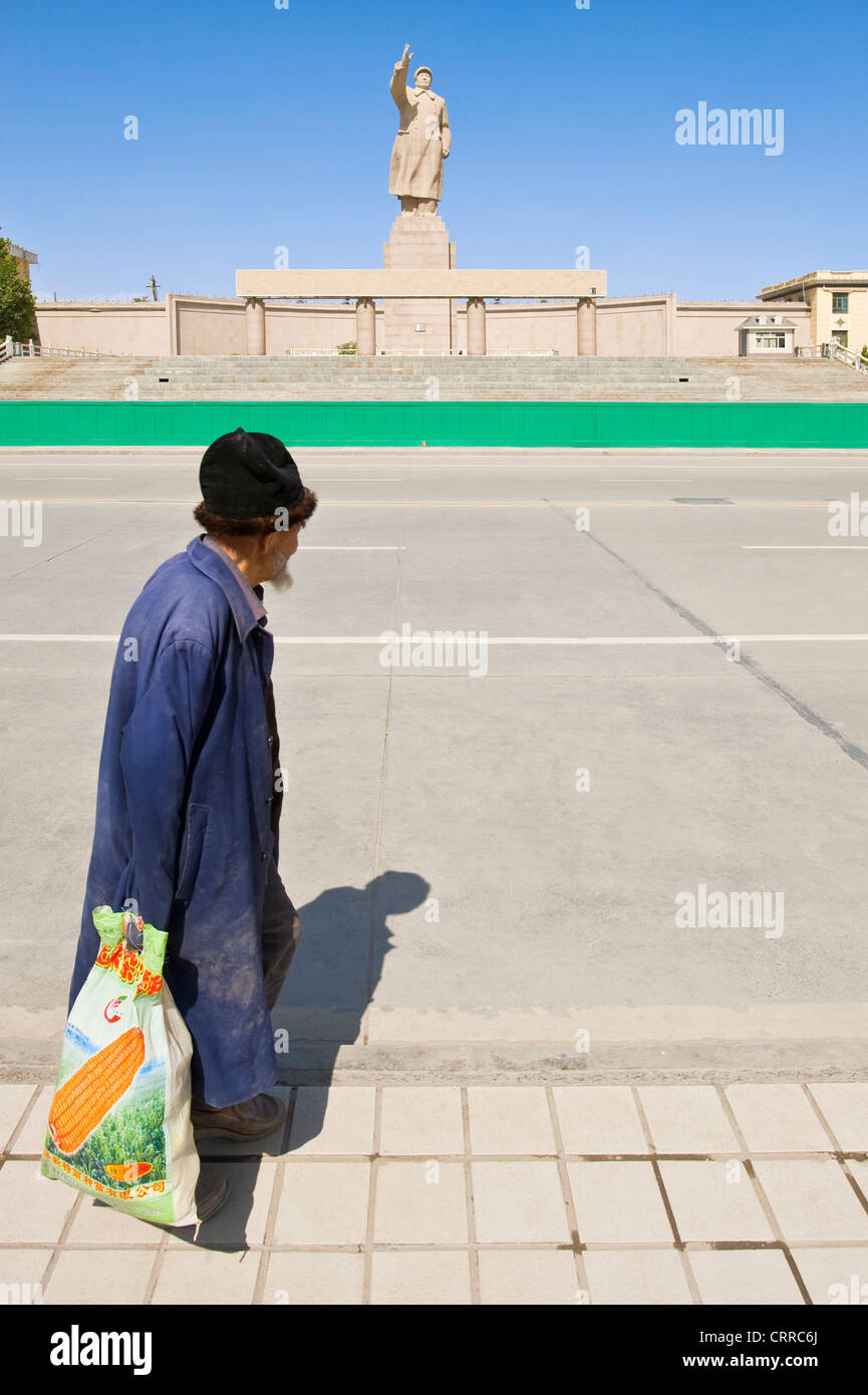 An elderly poor Chinese man walks past the statue of Mao Zedong in ...