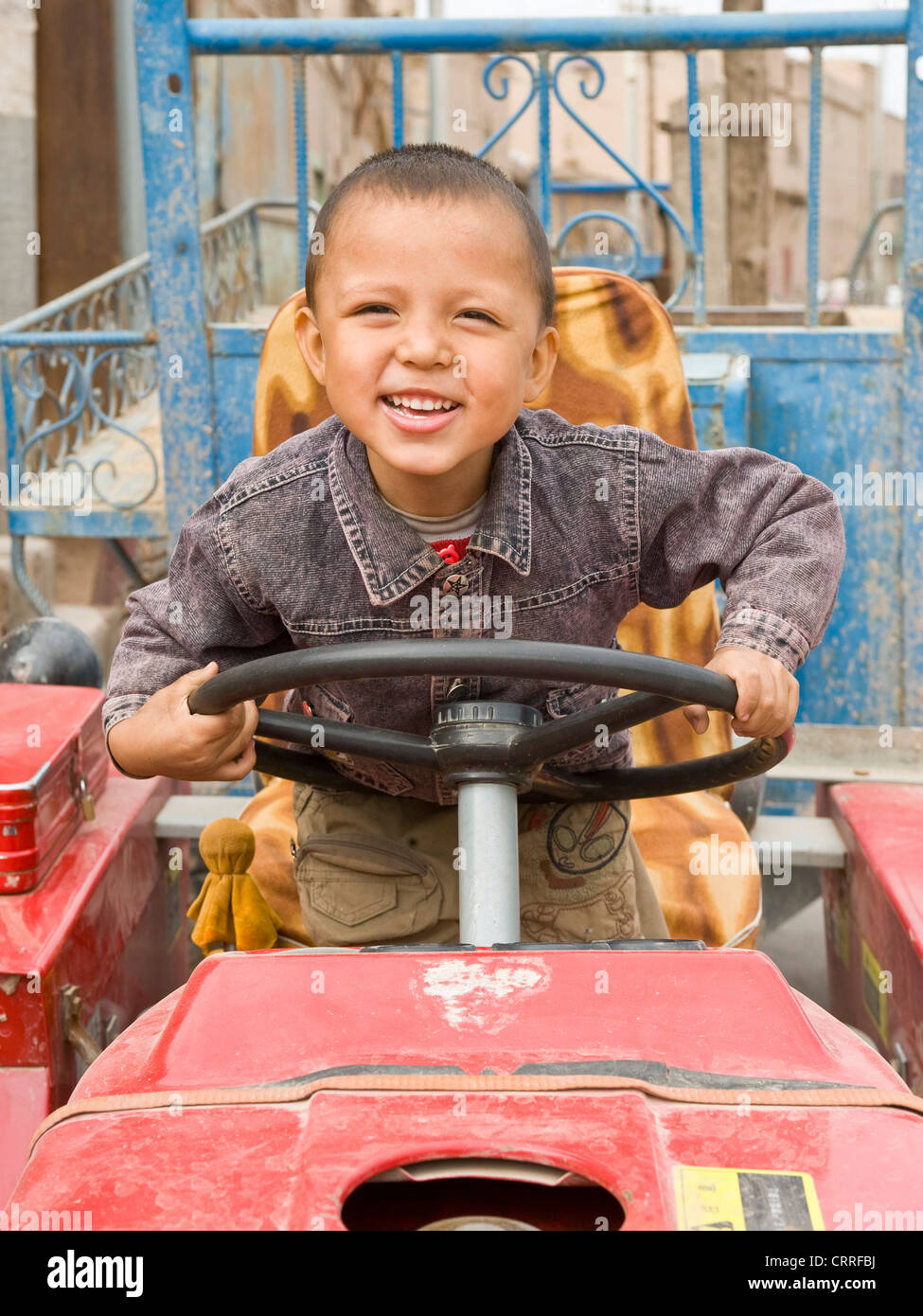 A young Uyghur Chinese boy poses for the camera in the street in the ...