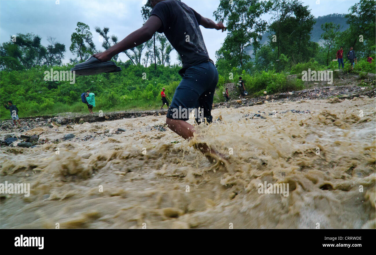 A man struggles to wade across a flooded road during monsoon season in ...