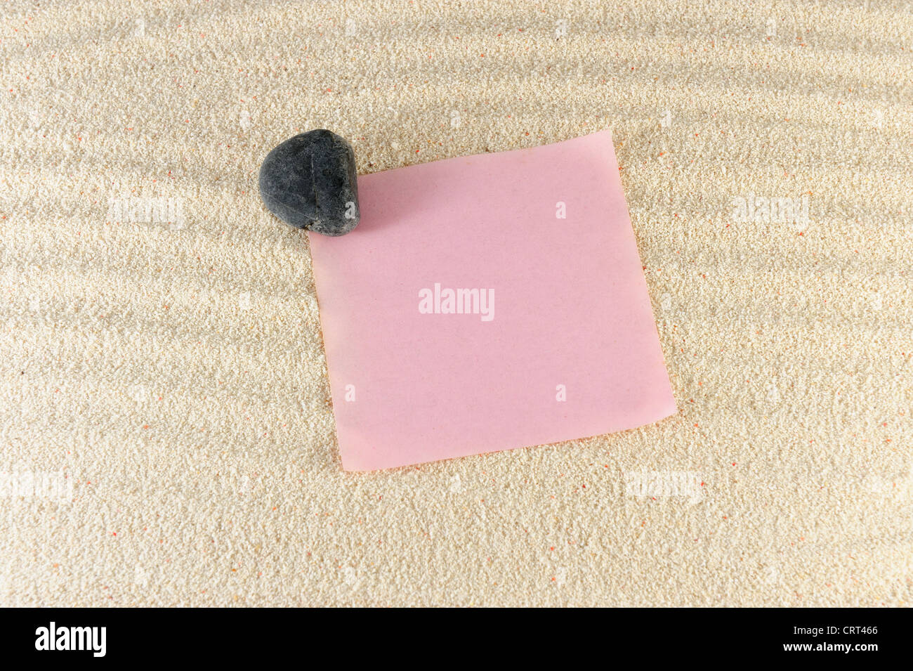 Blank paper on the sand with a stone on it Stock Photo - Alamy