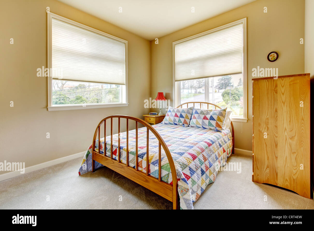 Simple bedroom with two large windows and wood bed Stock Photo - Alamy