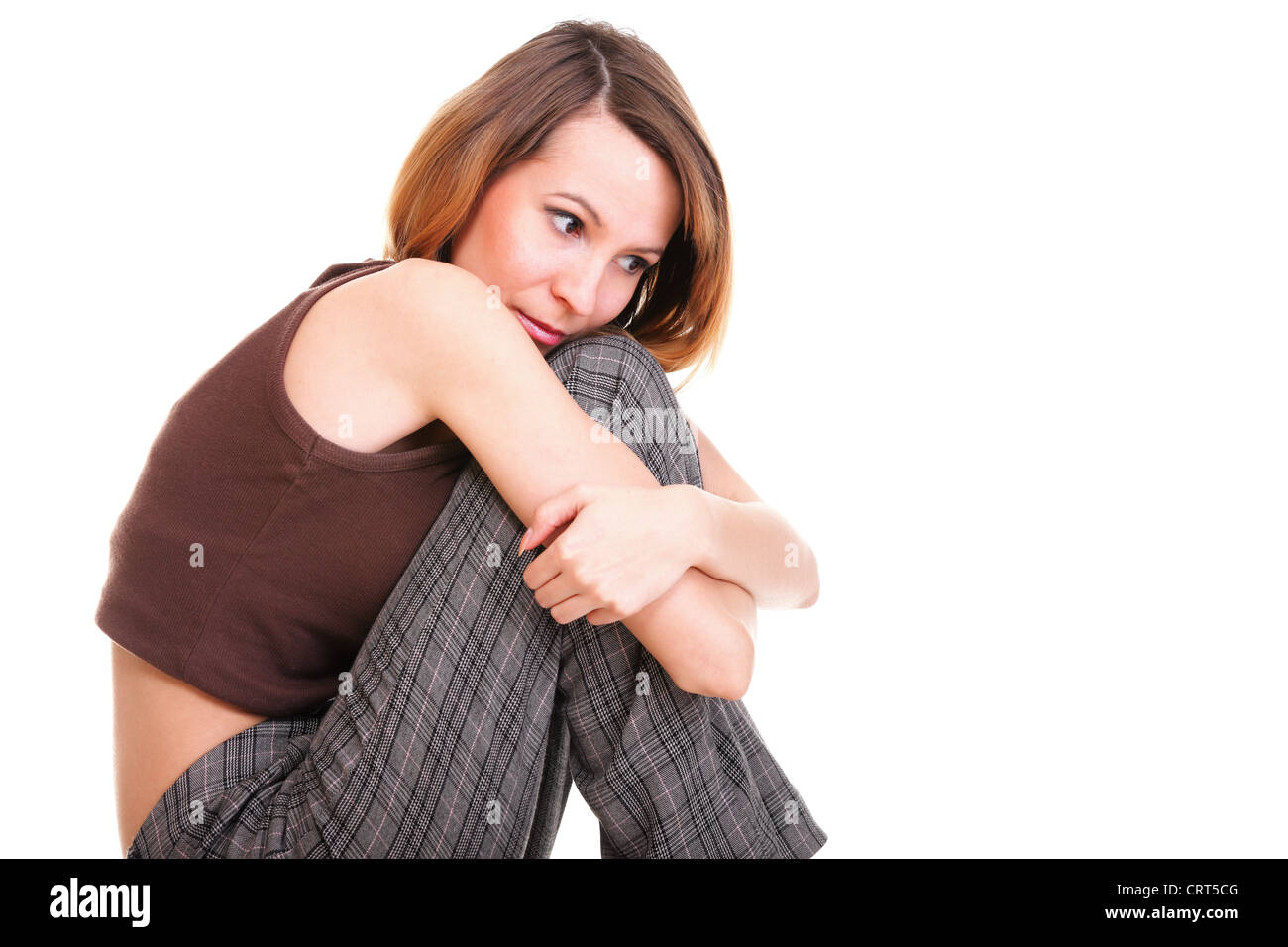 Portrait of young fit woman embracing her legs. Studio shot. Isolated ...