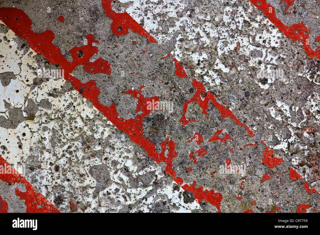 Detail of a pockmarked concrete wall painted in alternating bars of red ...