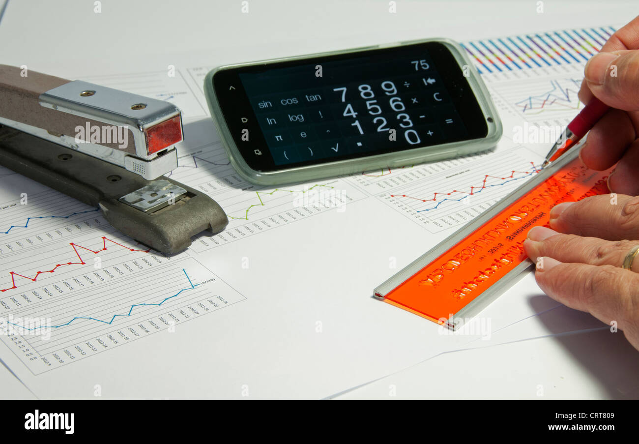 man making diagrams and graphics on a table with calculator and stapler ...
