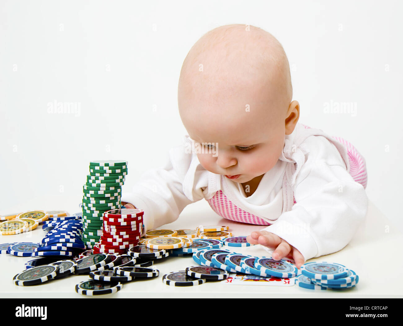 Lying on the table baby girl playing casino chips Stock Photo - Alamy