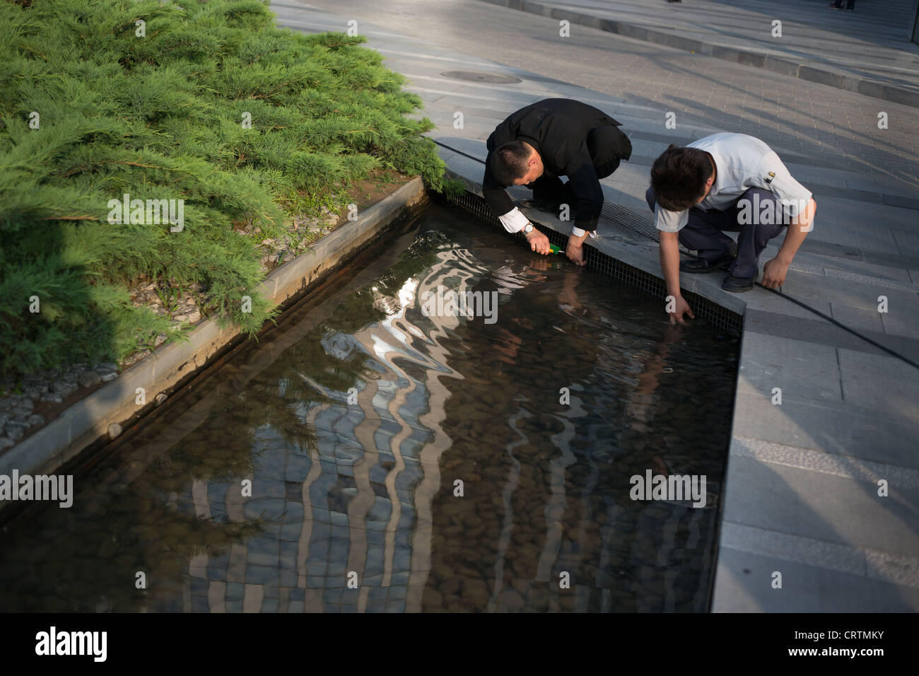 Men fixing a water feature in a public space in the Sanlitun upmarket ...