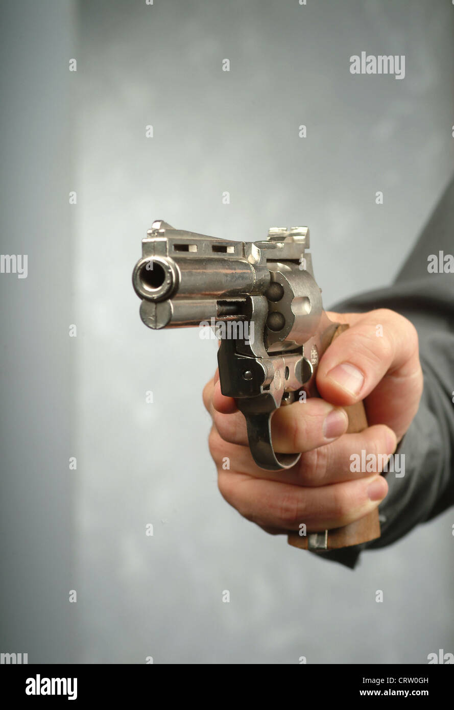 Hand with revolver ziehlt at viewer Stock Photo - Alamy