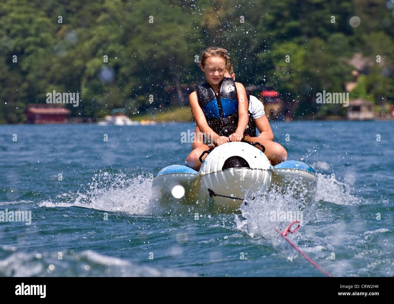 Two children riding a float being splashed by the water Stock Photo - Alamy