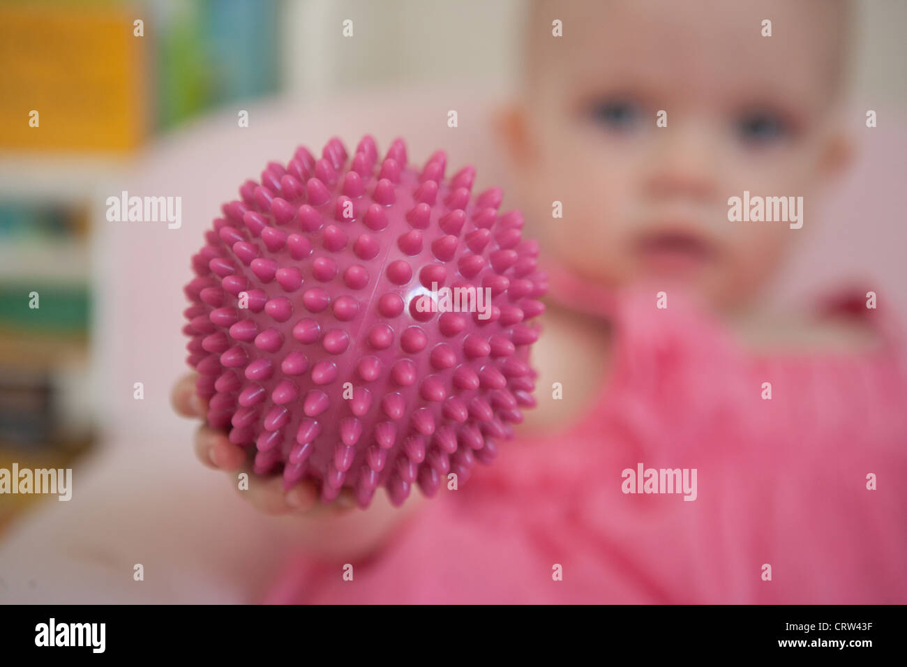 One year old girl holding large rubber spikey ball Stock Photo - Alamy