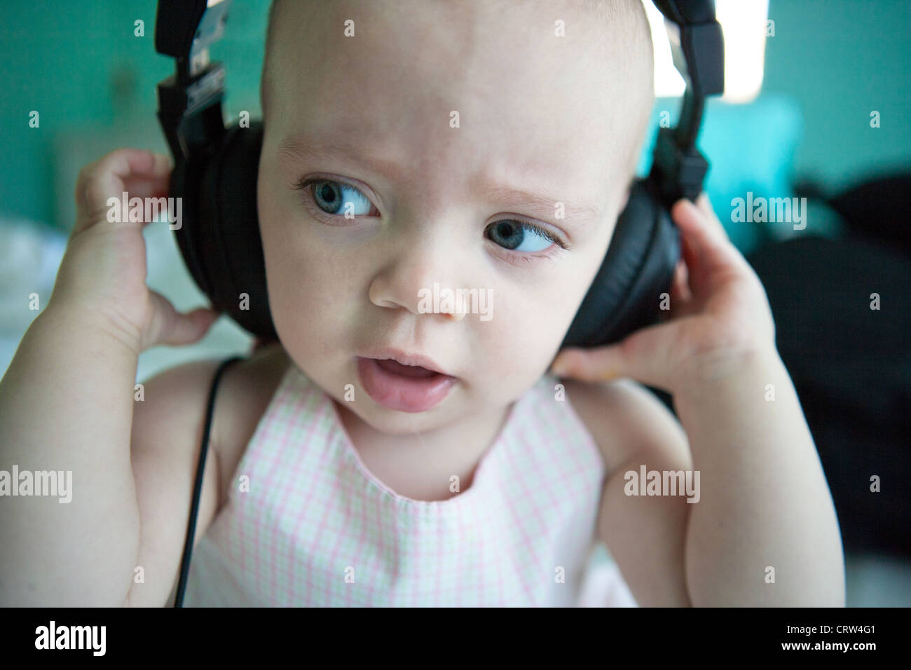 One year old listening intently to sound on headphones, closeup Stock ...