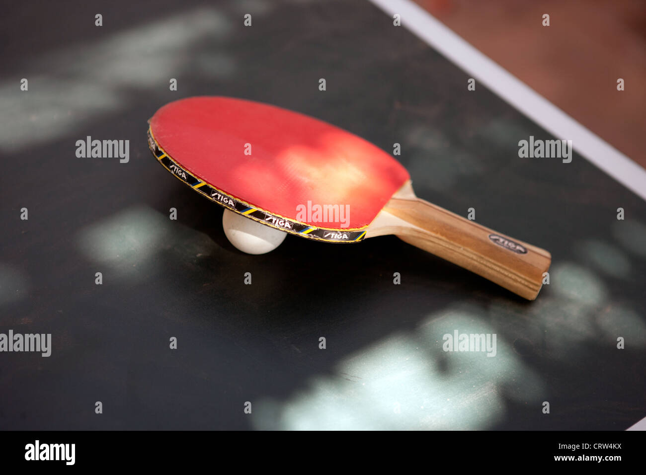 Ping pong paddle and ball on a table tennis surface Stock Photo - Alamy