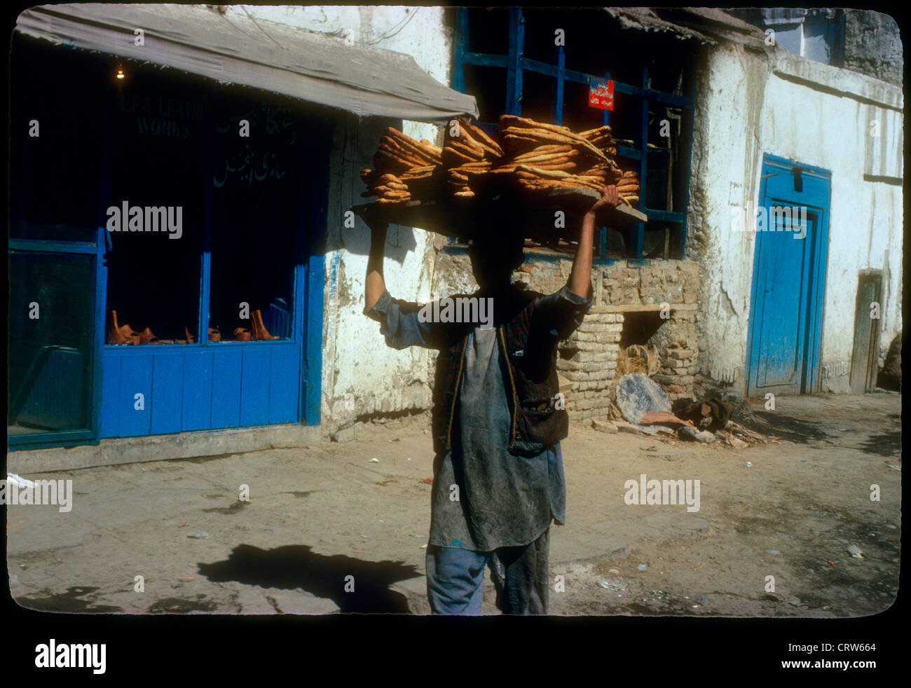 Man carrying freshly baked bread through street in afghanistan before ...