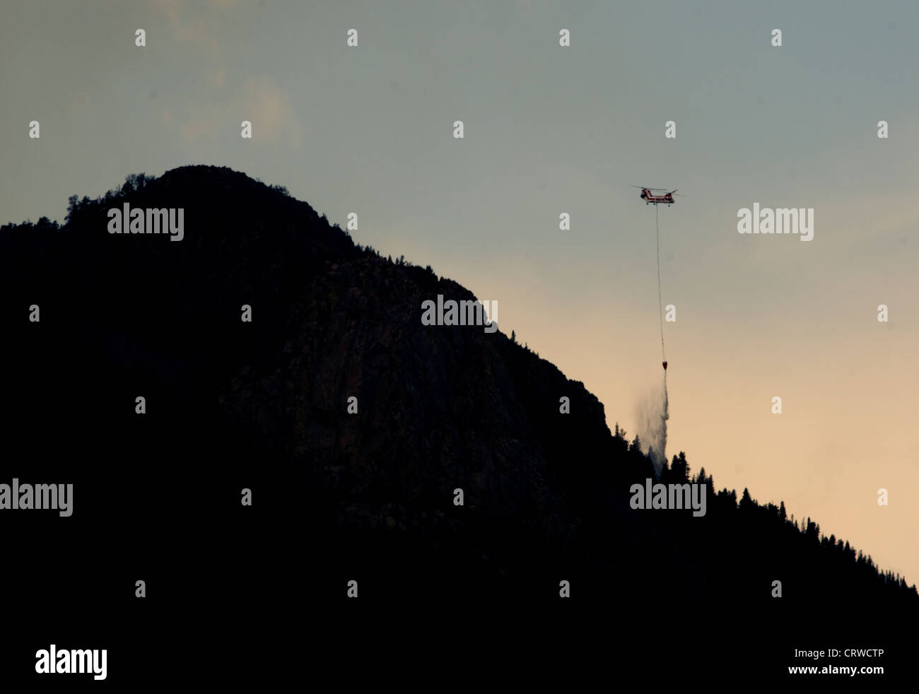 A helicopter contracted by the U.S. Forest Service drops retardant in ...