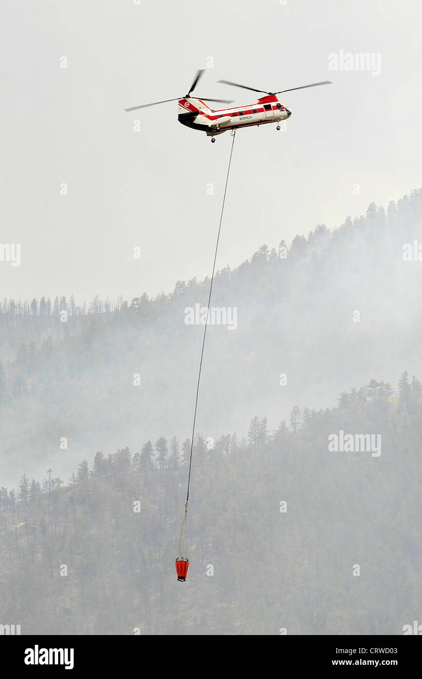A firefighting Chinook helicopter scoops up water out of a pond while ...