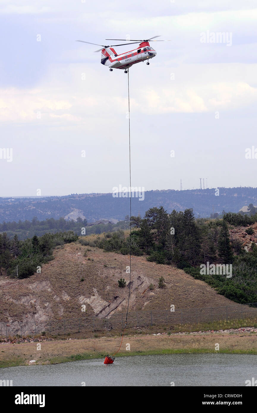 A firefighting Chinook helicopter scoops up water out of a pond while ...