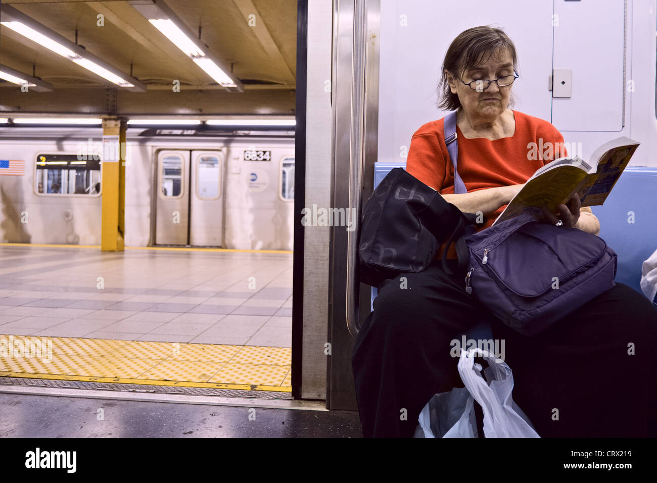 Woman reading book on subway Stock Photo - Alamy