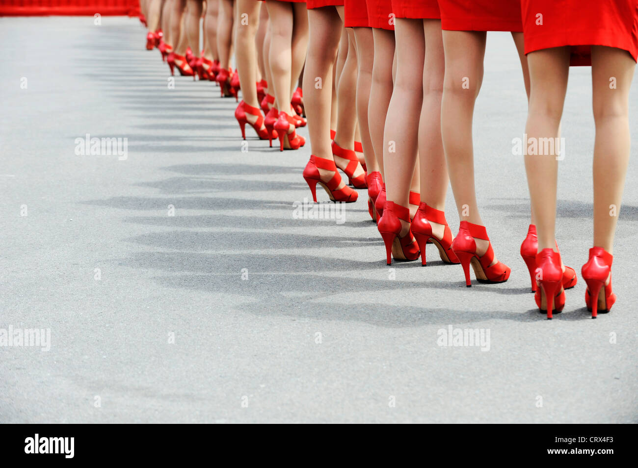 women wearing red dresses and red high-heeled shoes stand in a row ...