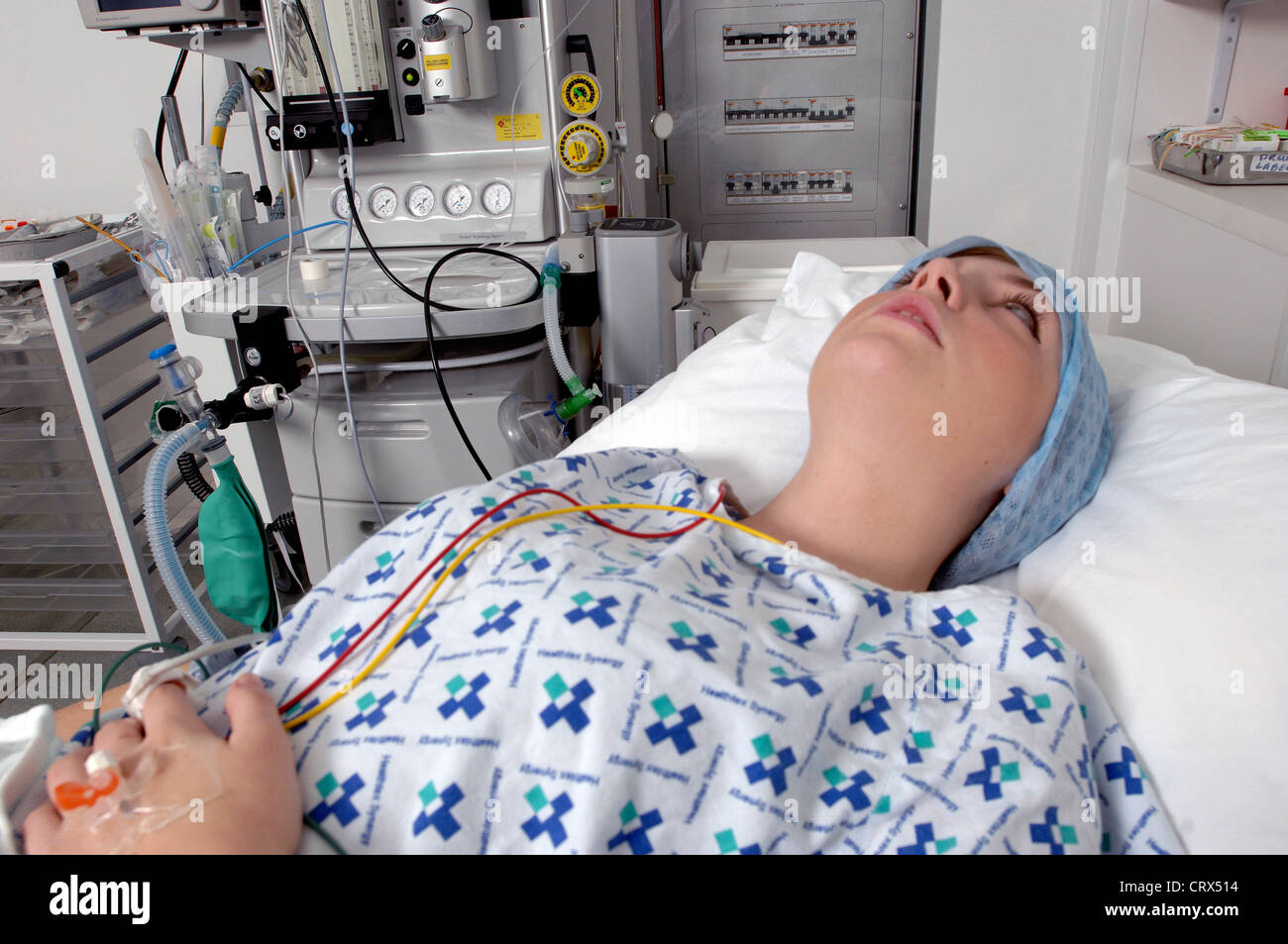 A young female patient, wearing a blue surgical cap, in an operating ...