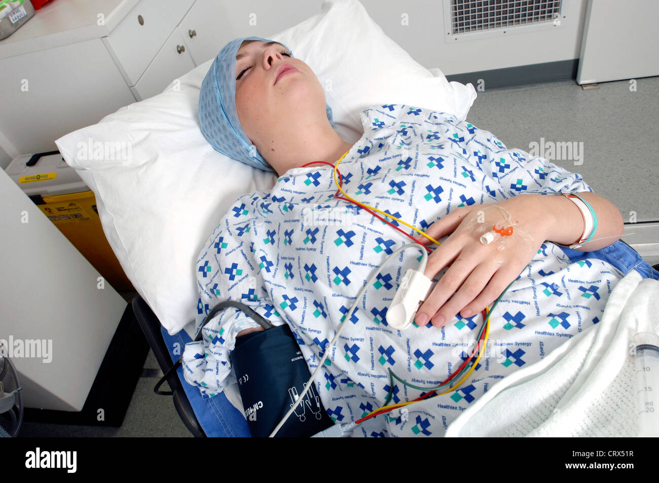 A female patient lies asleep, in a bed, wearing a pulse oximeter on her ...