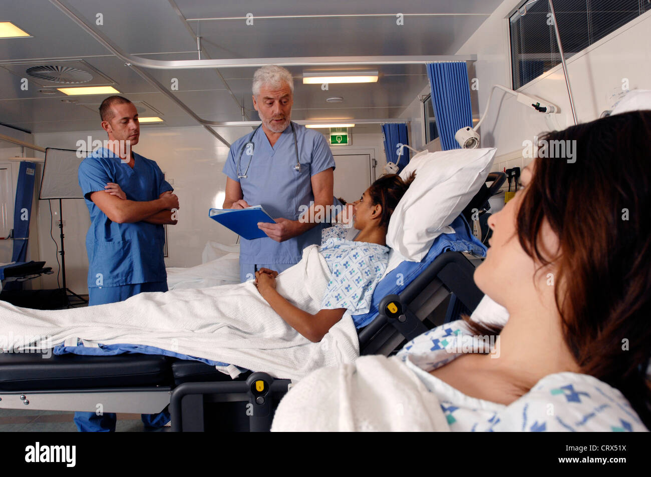 Doctors check the health of patient as she lays in her hospital bed ...