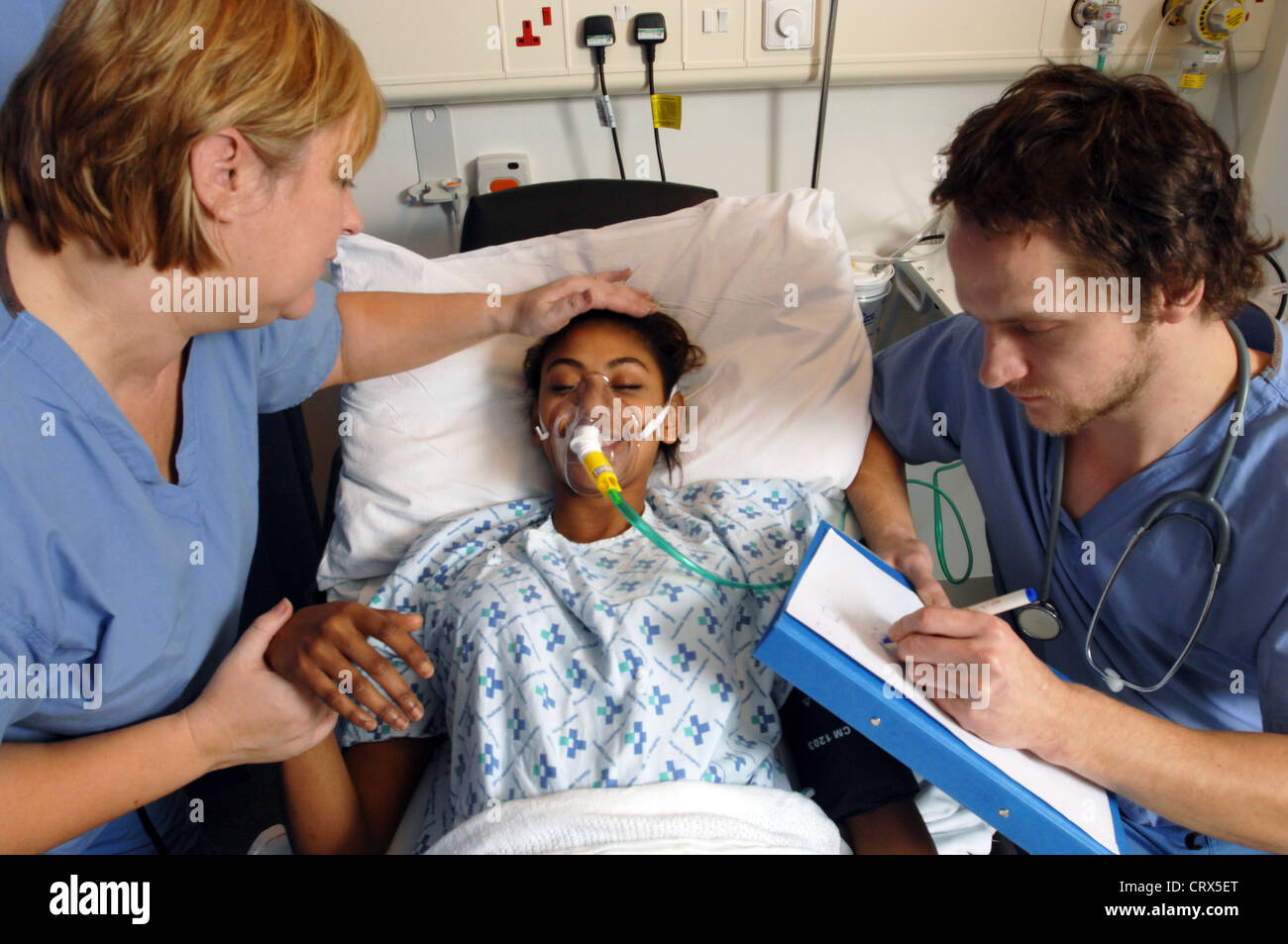 Two doctors seeing to a female patient Stock Photo - Alamy