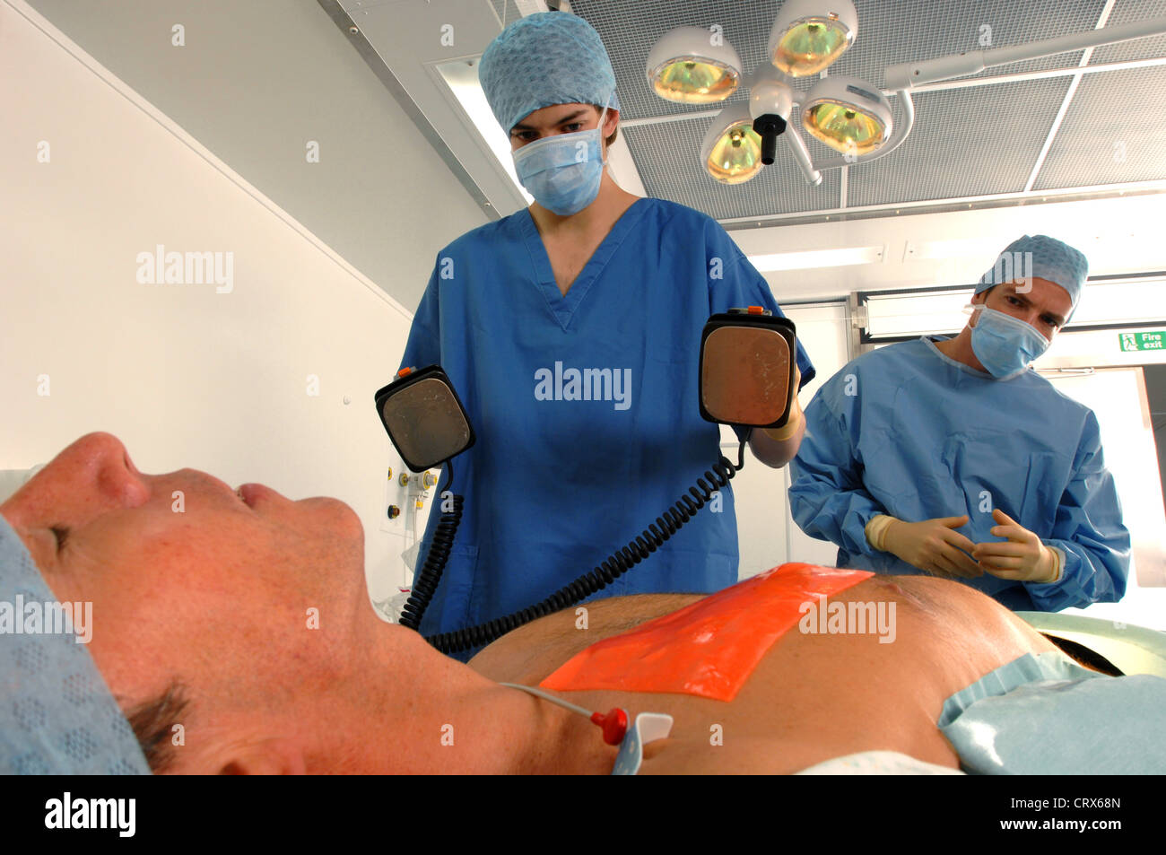 Doctors using a defibrillator to resuscitate a male heart attack victim ...